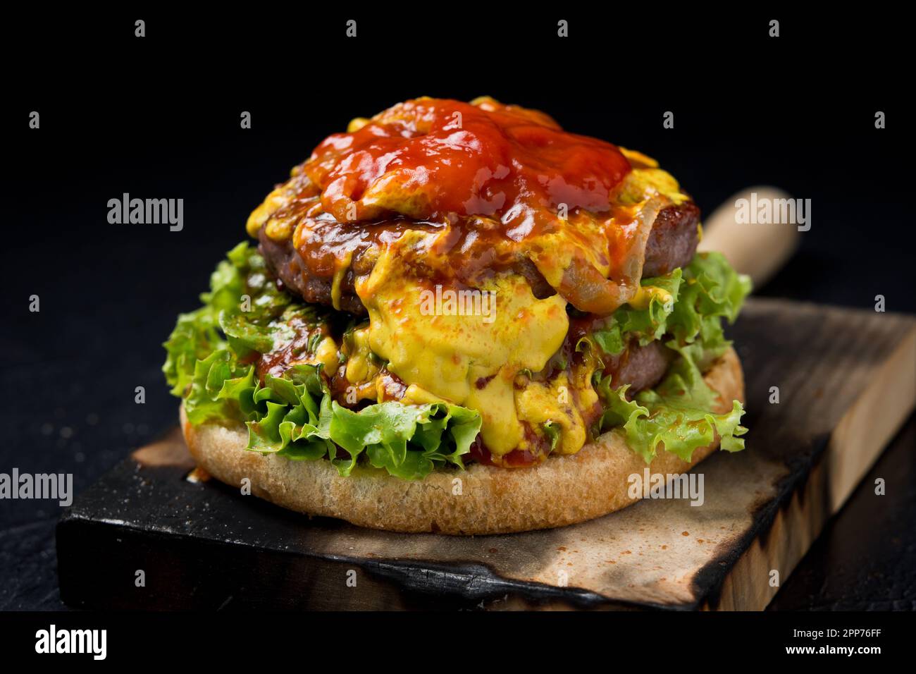 Beef burger. With mustard and ketchup, lettuce and onion. Black ...