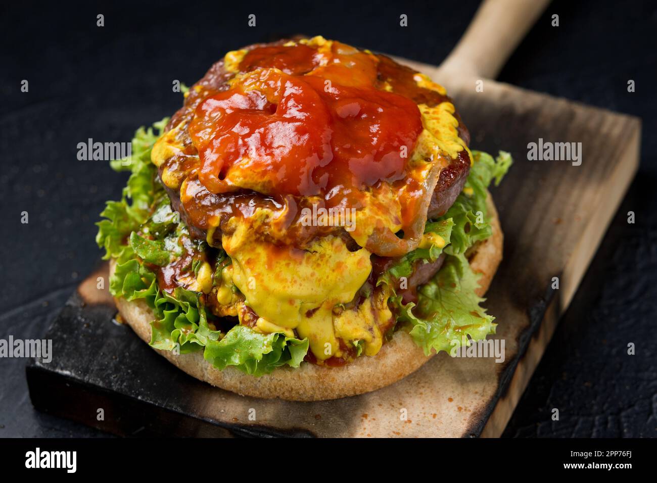 Beef burger. With mustard and ketchup, lettuce and onion. Black ...