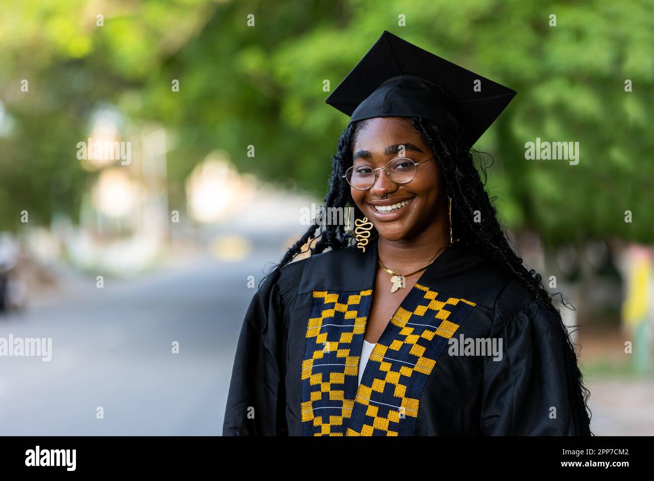 Black Female University Graduate wearing black gown and cap, proud of ...