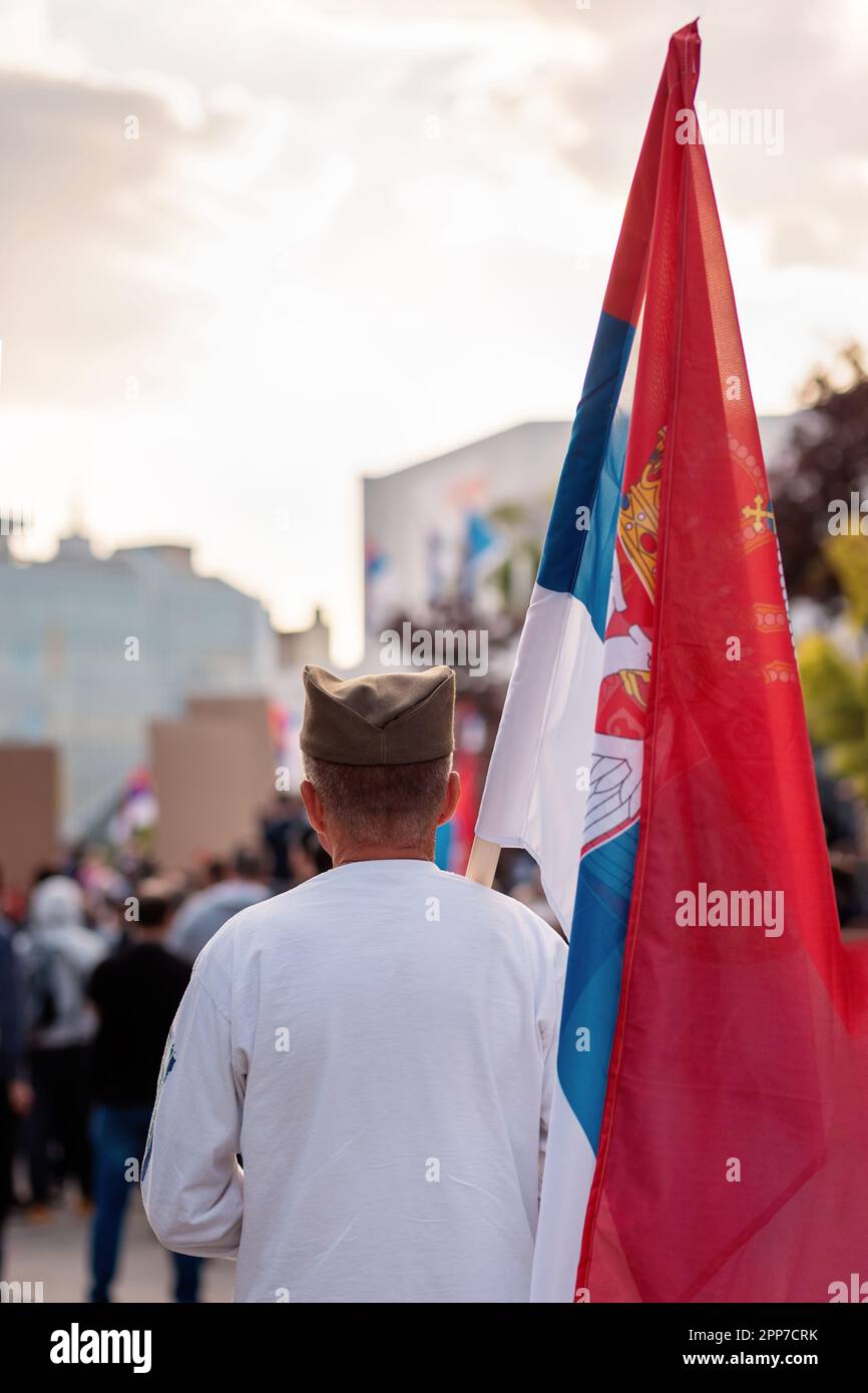 Back view of political rally of people. Man patriot holds serbian flag ...