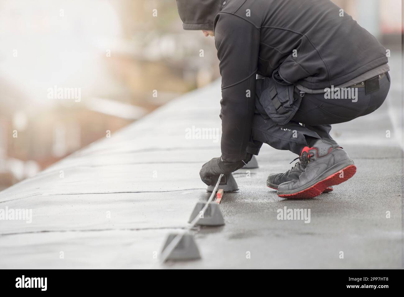 Ground wire. A worker lays a ground cable on the roof of a building ...