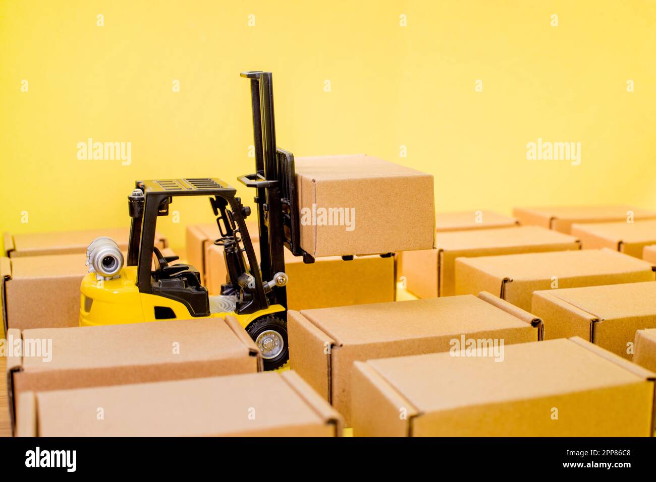 Forklift truck raises cardboard boxes on a yellow background. Cargo ...