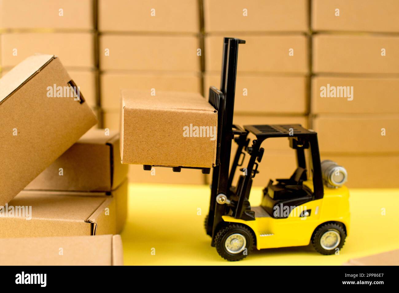 Forklift truck raises cardboard boxes on a yellow background. Cargo ...