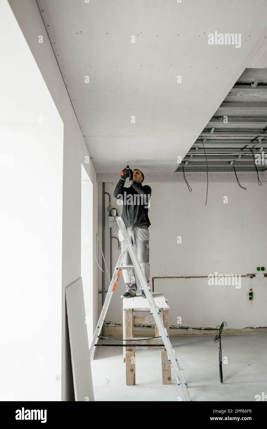 Construction worker assemble a suspended ceiling with drywall and ...