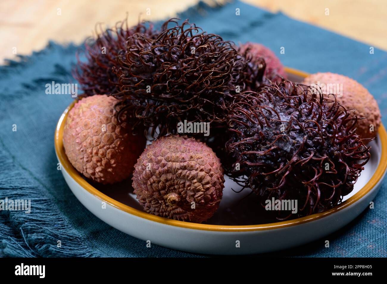 Tasty tropical exotic fruits, ripe fresh unpeeled lychee and hairy ...