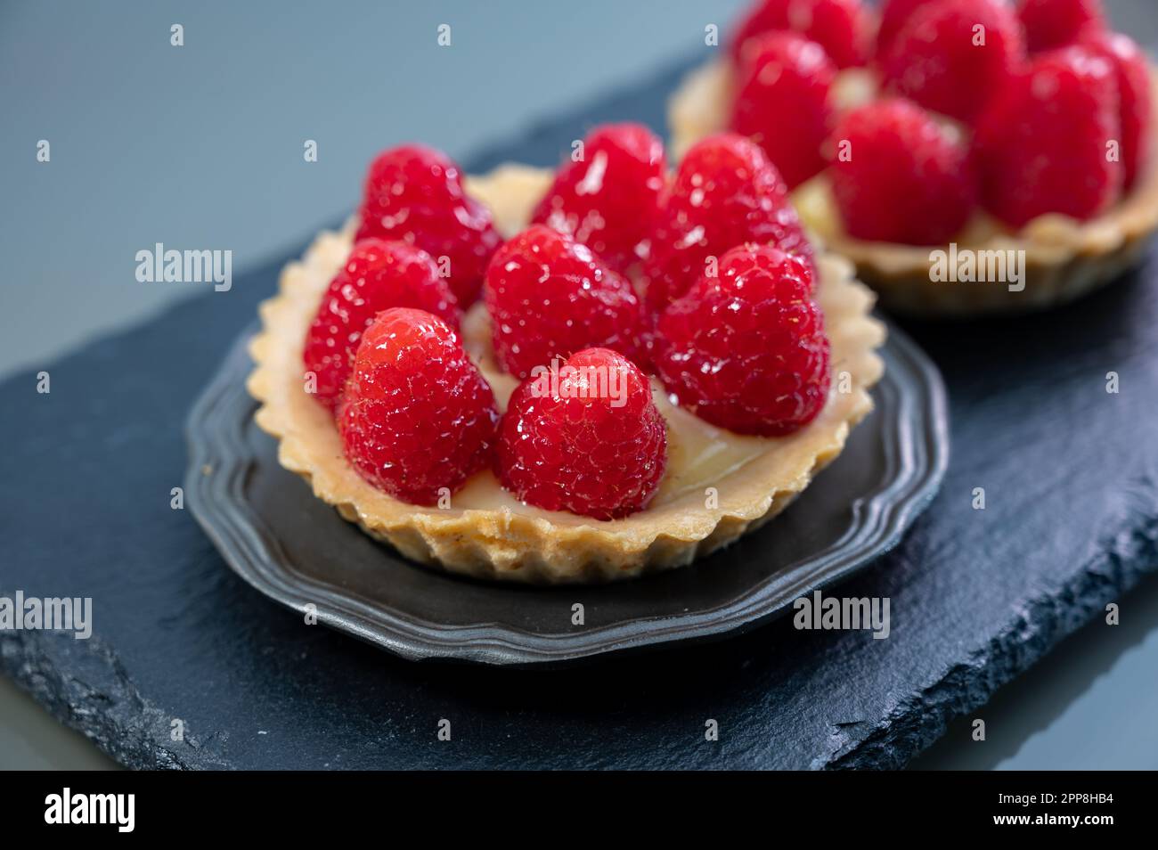 Artisanal baked small tart with cream and fresh ripe red raspberry ...