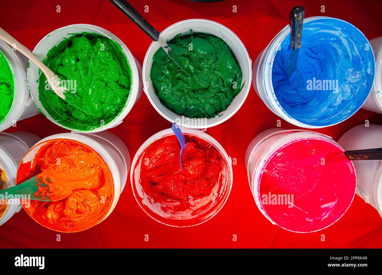 Top view, colorful fabric printing inks in white buckets. Stirring the ...