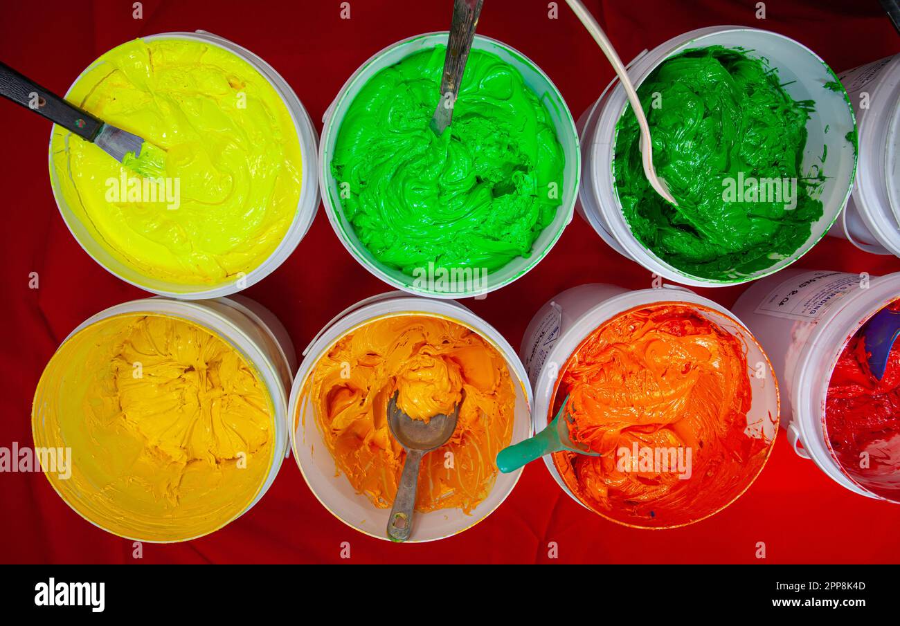 Top view, colorful fabric printing inks in white buckets. Stirring the ...