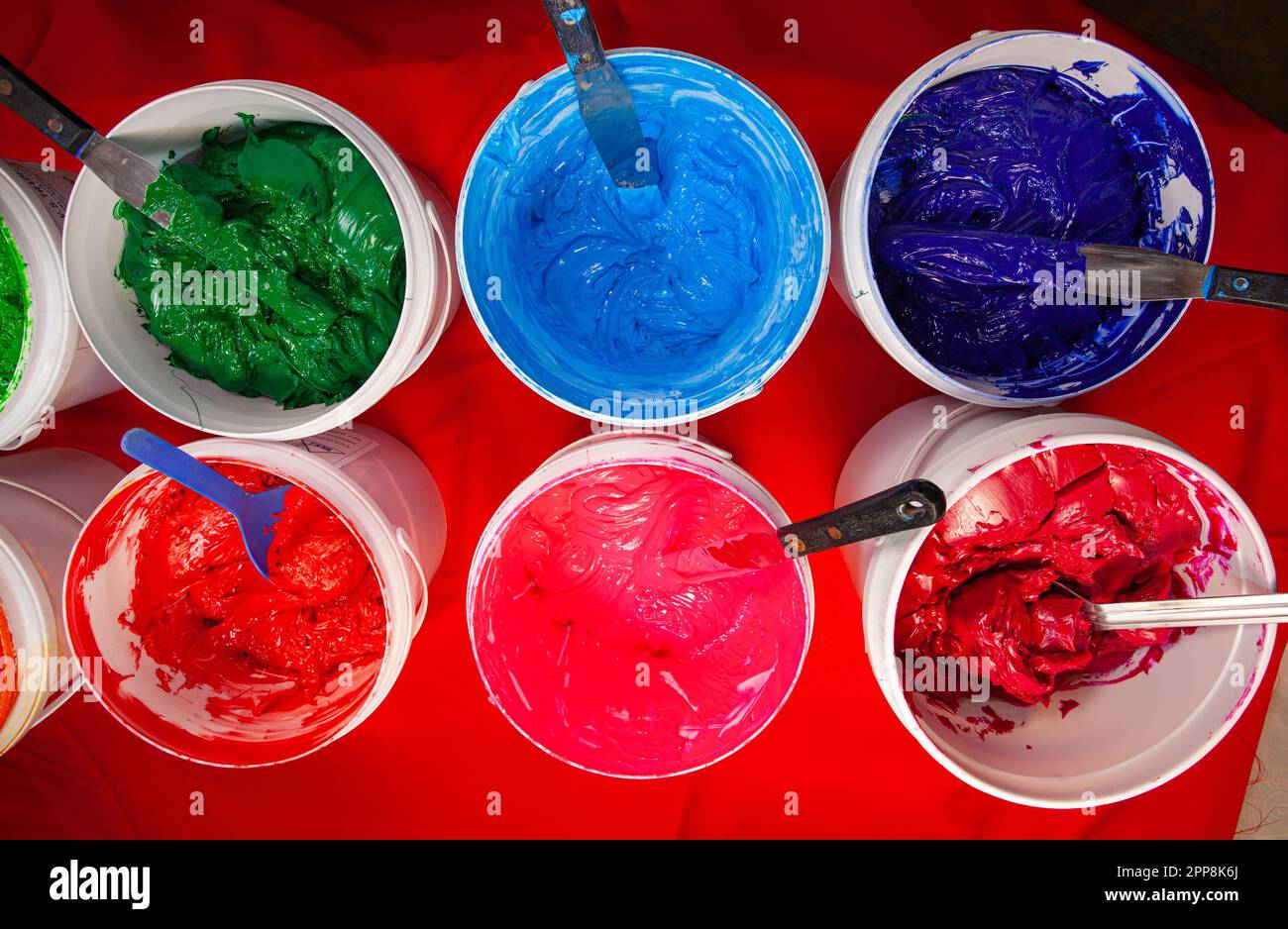 Top view, colorful fabric printing inks in white buckets. Stirring the ...