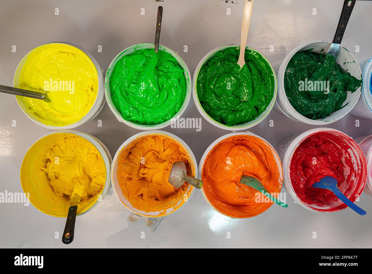 Top view, colorful fabric printing inks in white buckets. Stirring the ...