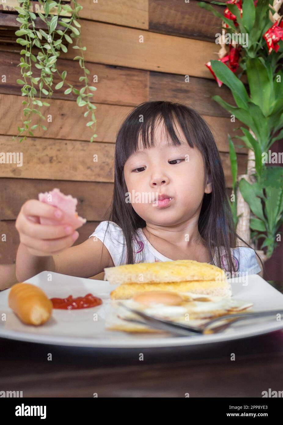 Asian girl child eating american breakfast Stock Photo - Alamy