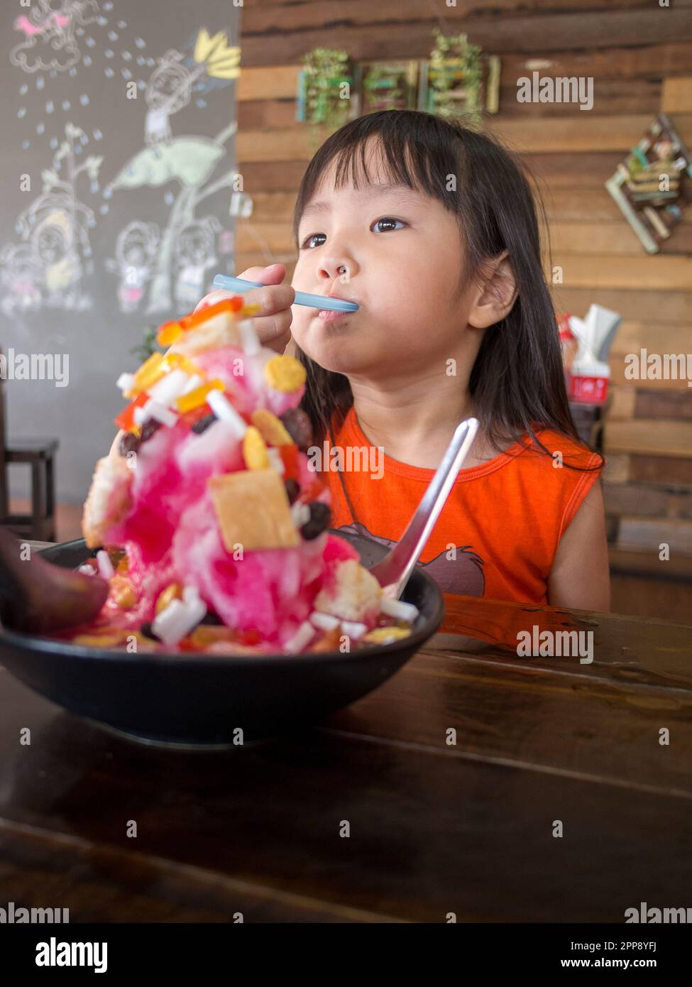 Asian girl child eating a dessert Stock Photo - Alamy