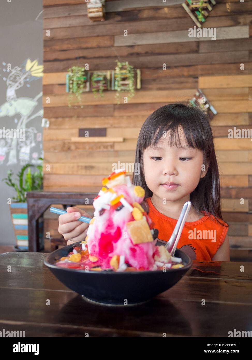 Asian girl child eating a dessert Stock Photo - Alamy