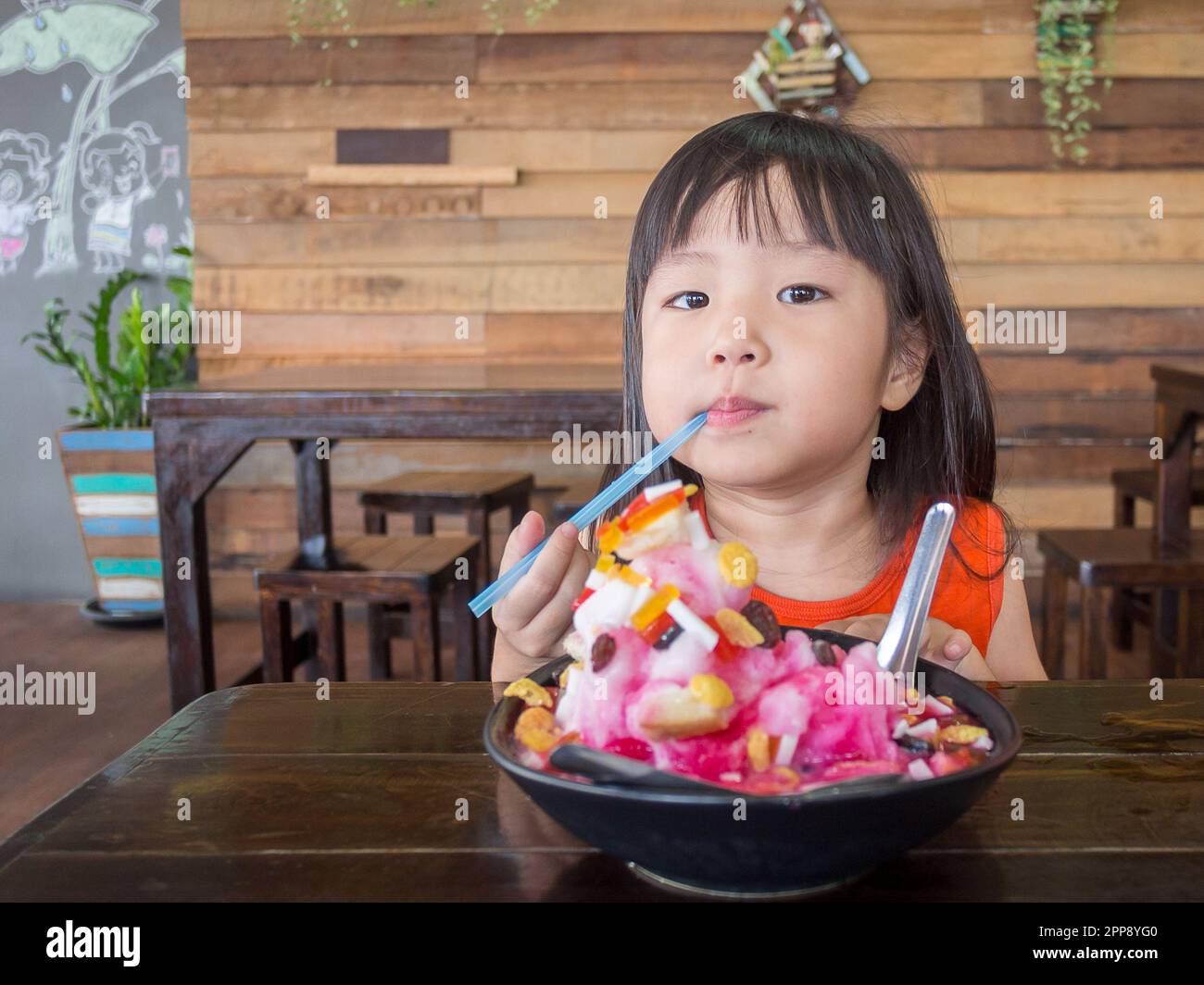 Asian girl child eating a dessert Stock Photo - Alamy