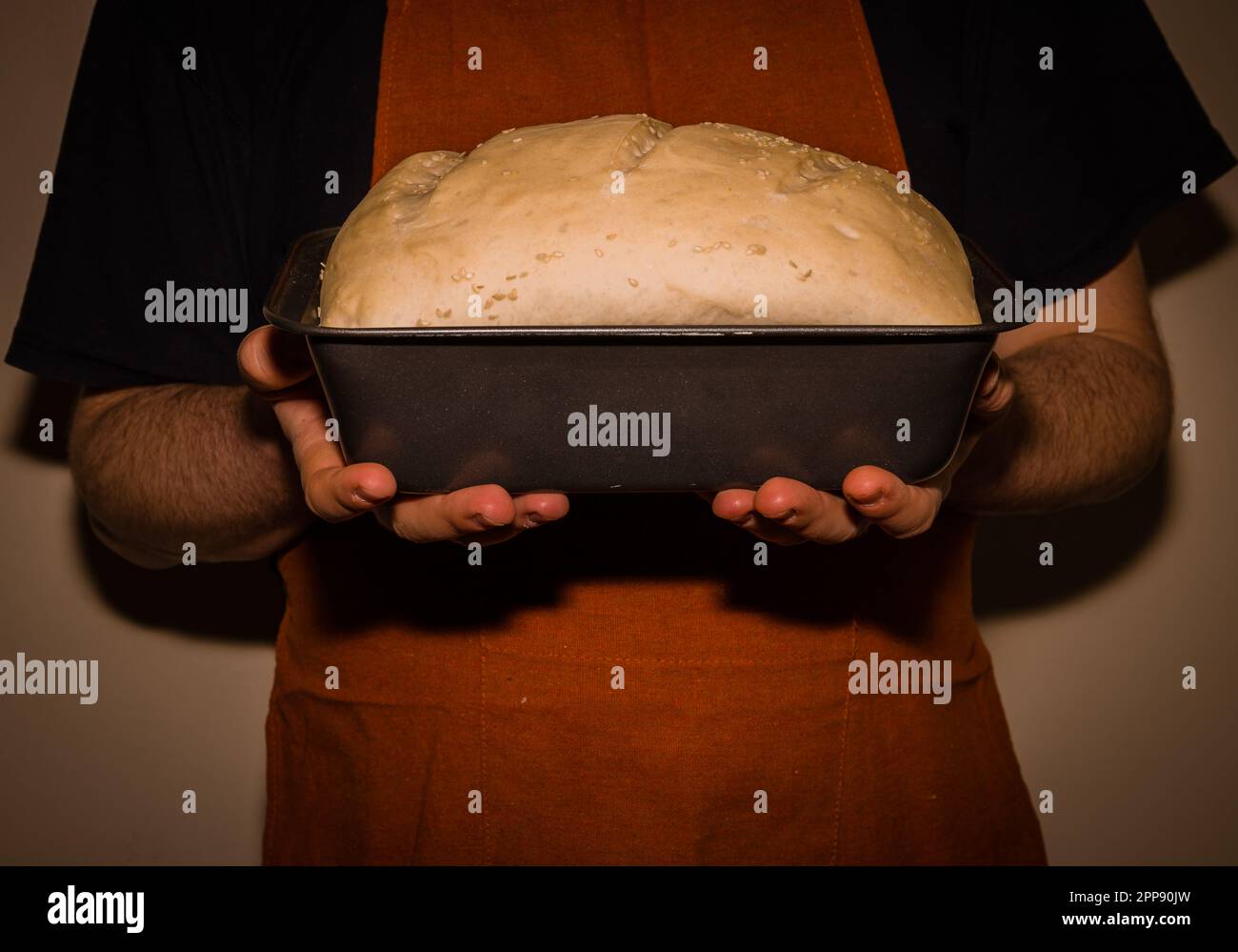 Baker in apron holding a homemade rised bread dough. An old-style home ...