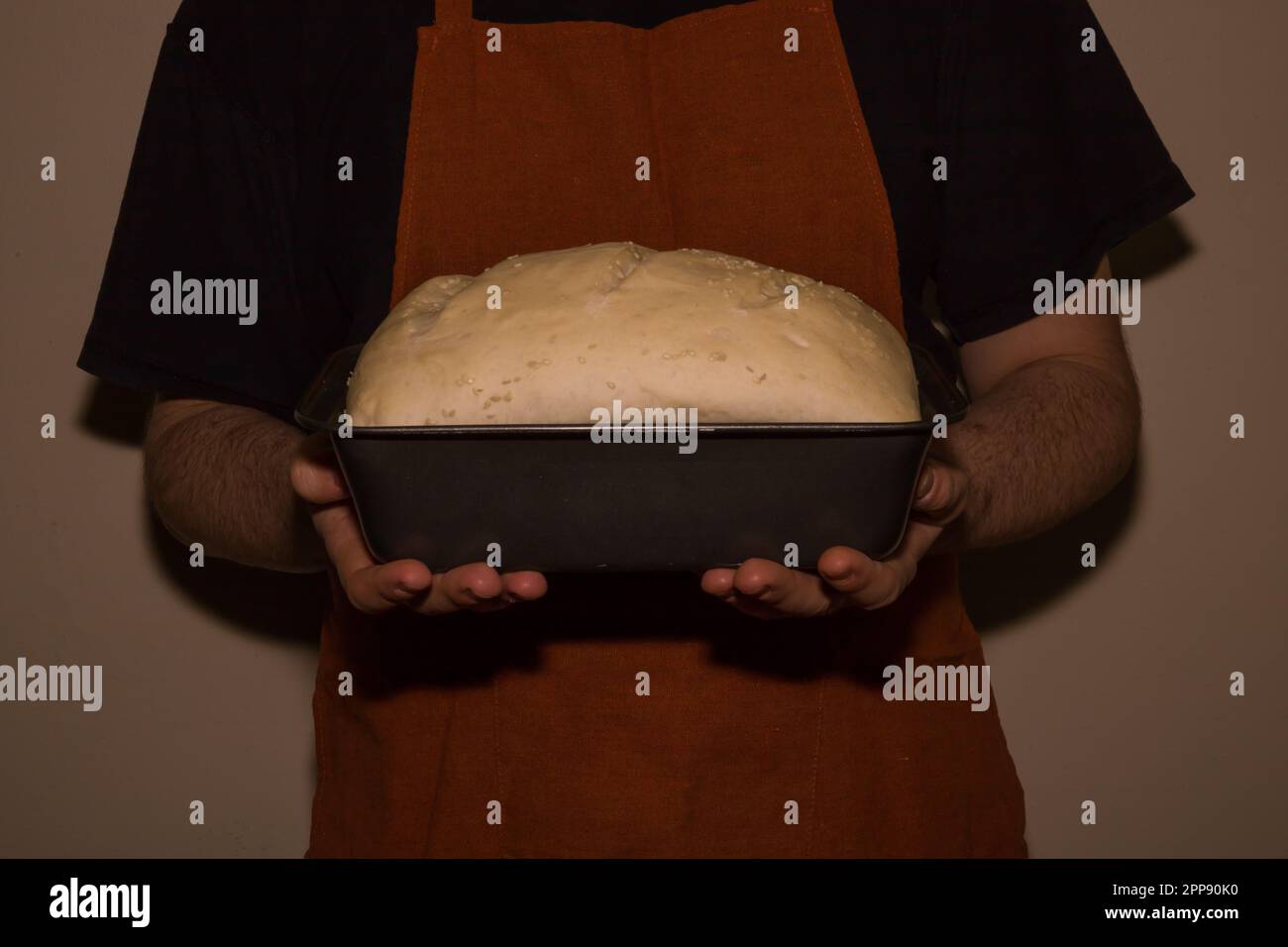 Baker in apron holding a homemade rised bread dough. An old-style home ...