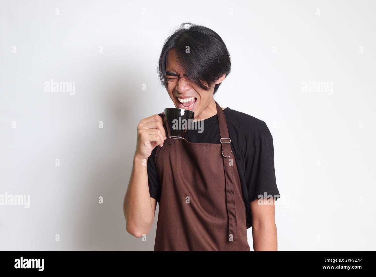 Portrait of attractive Asian barista man in brown apron making ...