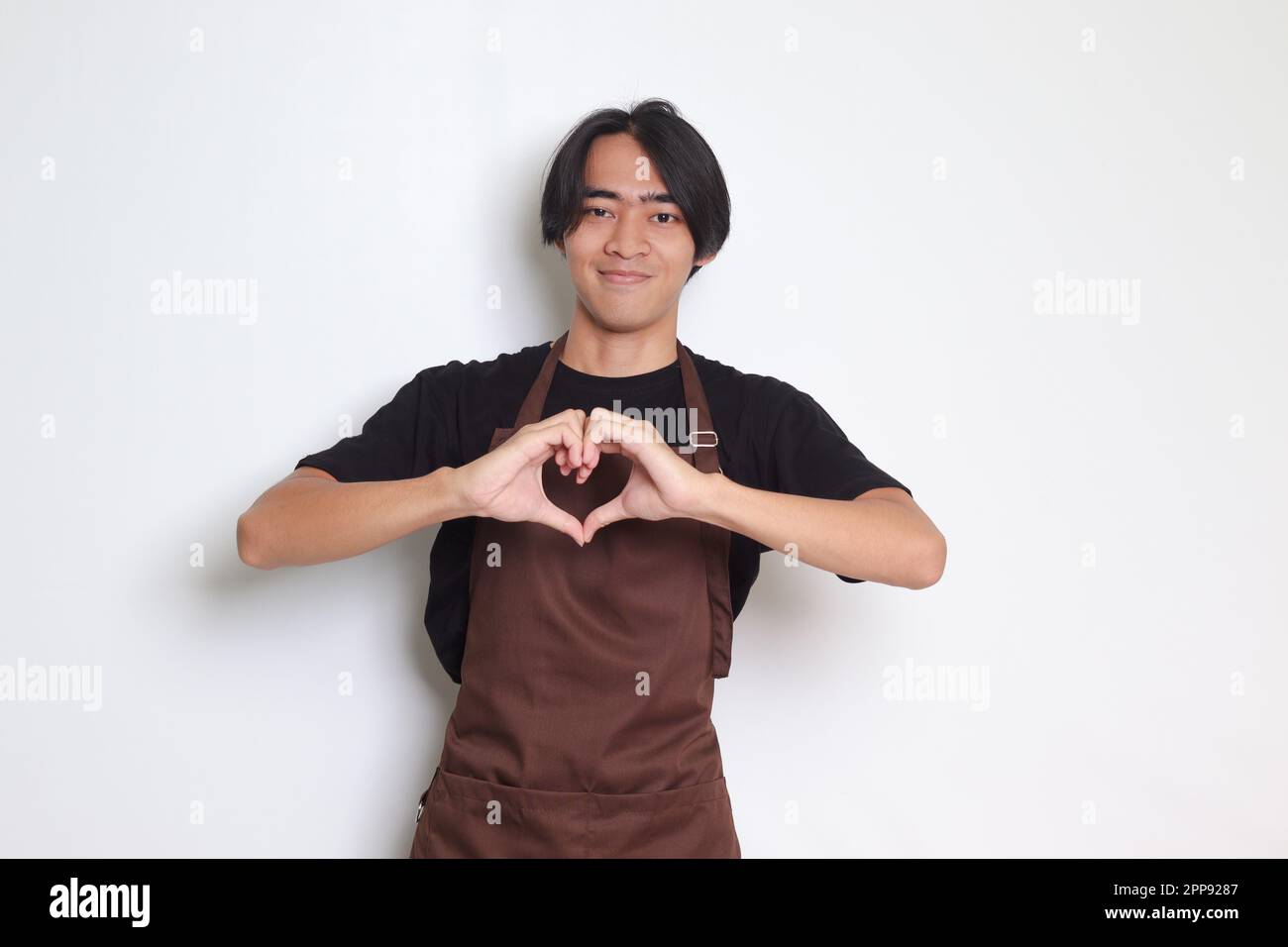 Portrait of attractive Asian barista man in brown apron speaks about ...