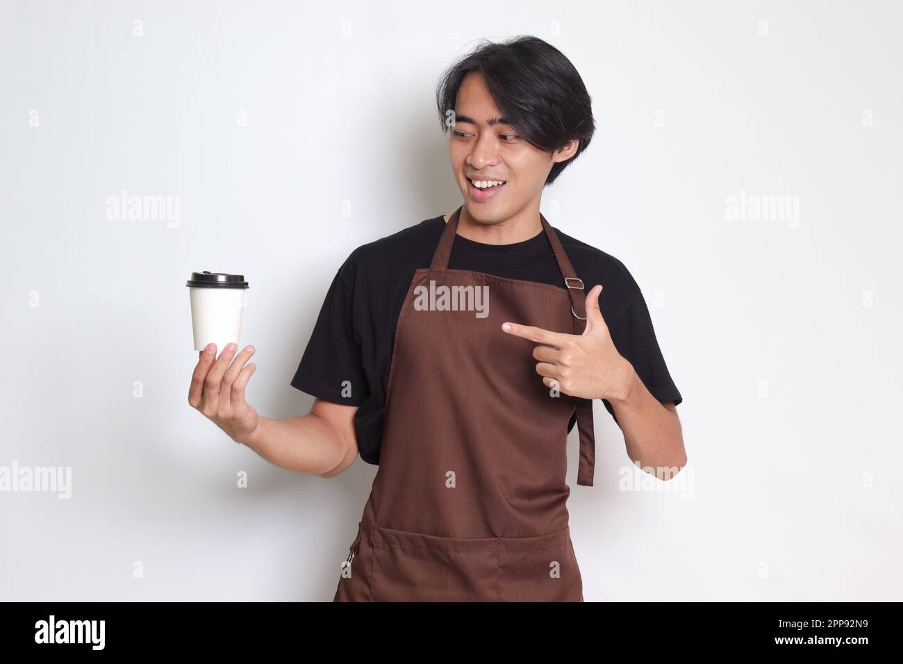 Portrait of attractive Asian barista man in brown apron holding take ...