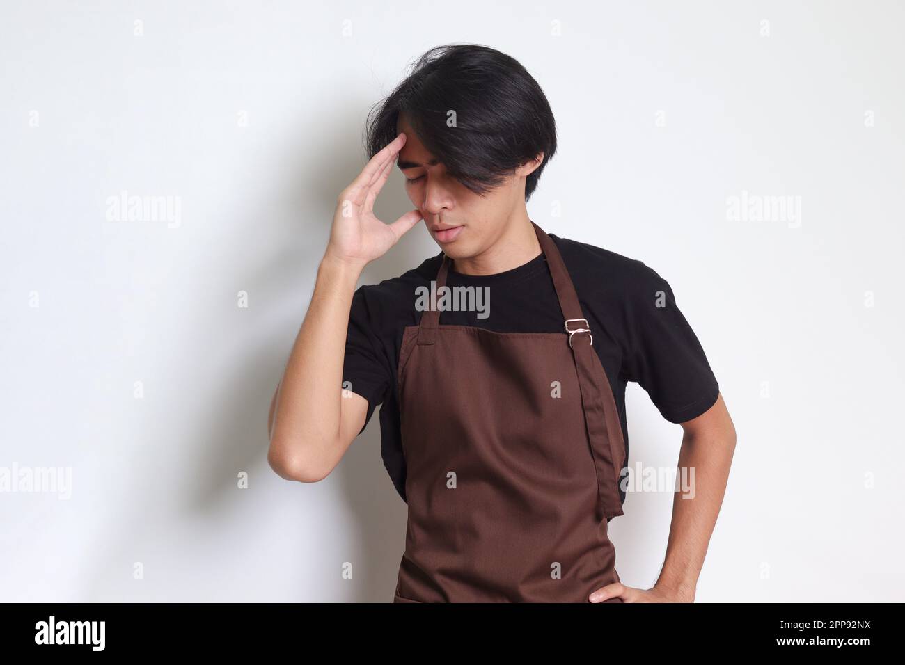 Portrait of attractive Asian barista man in brown apron holding hand on ...