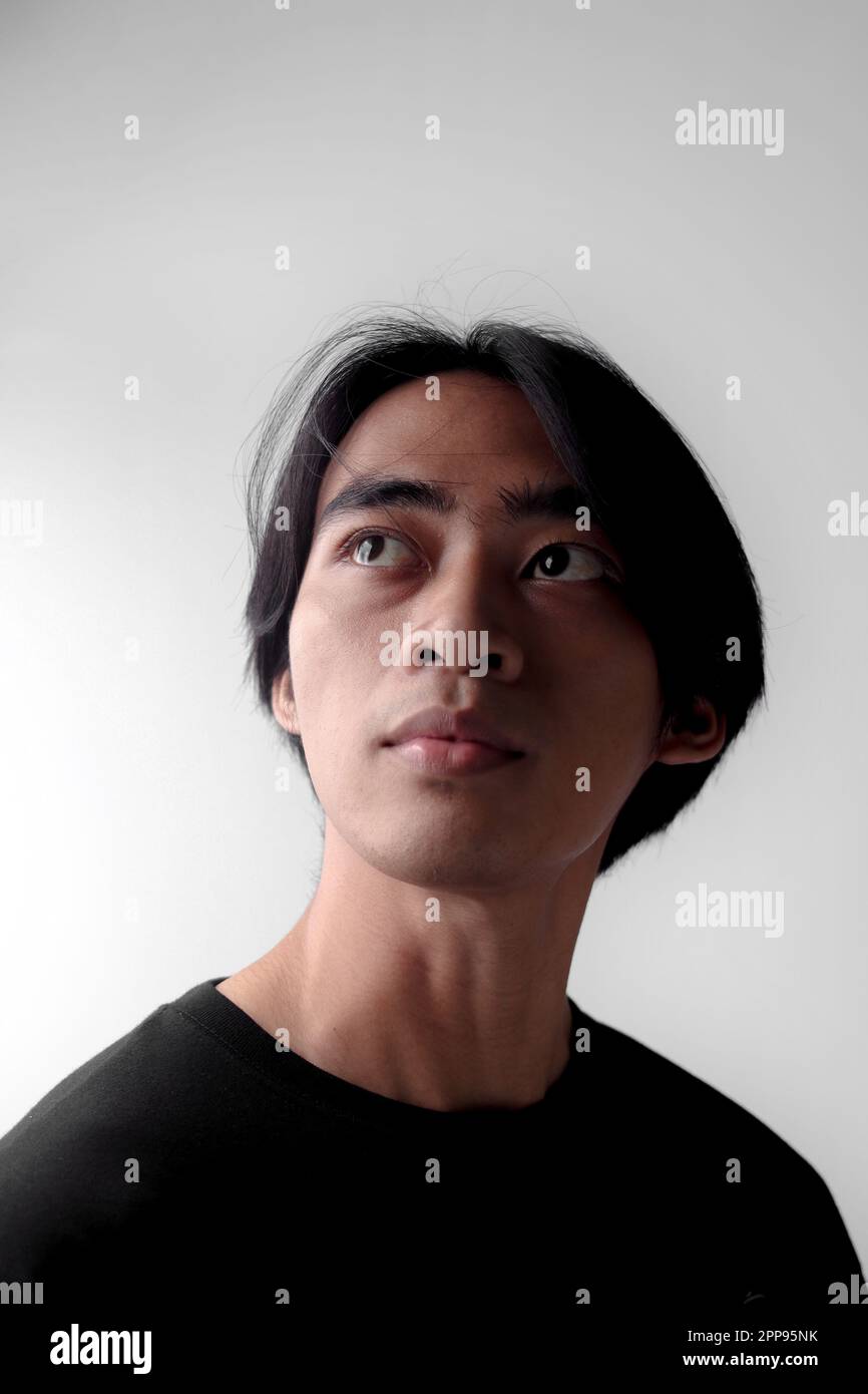 Dramatic low light portrait of handsome Asian man looking up. Side ...