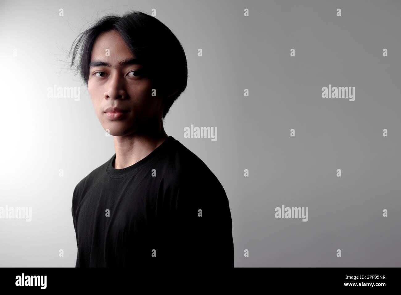 Dramatic low light portrait of handsome Asian man looking up. Side ...