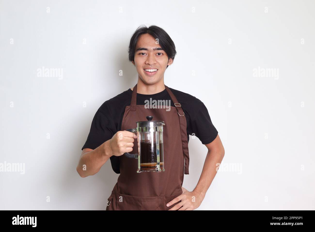 Portrait of attractive Asian barista man in brown apron pointing with ...