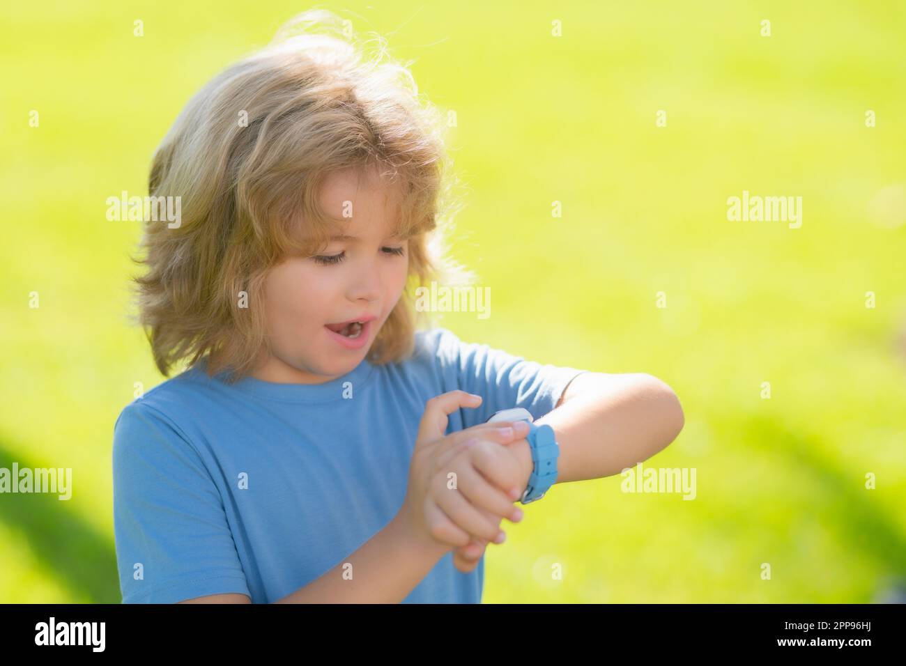 Child checking smart watch, looks on the time and hurrying. Portrait of ...