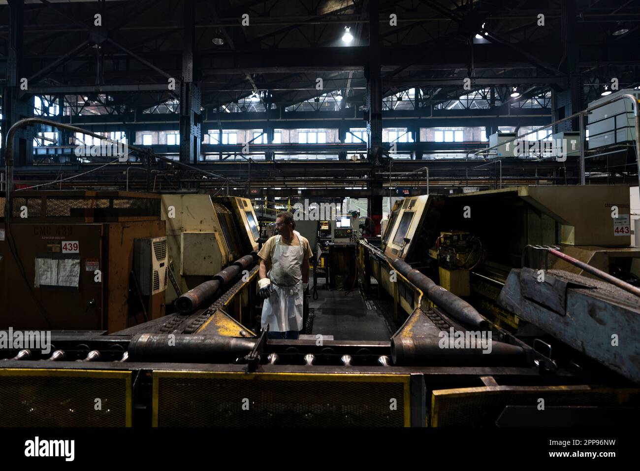 A steel worker operates a machine used in the manufacturing of 155 mm ...