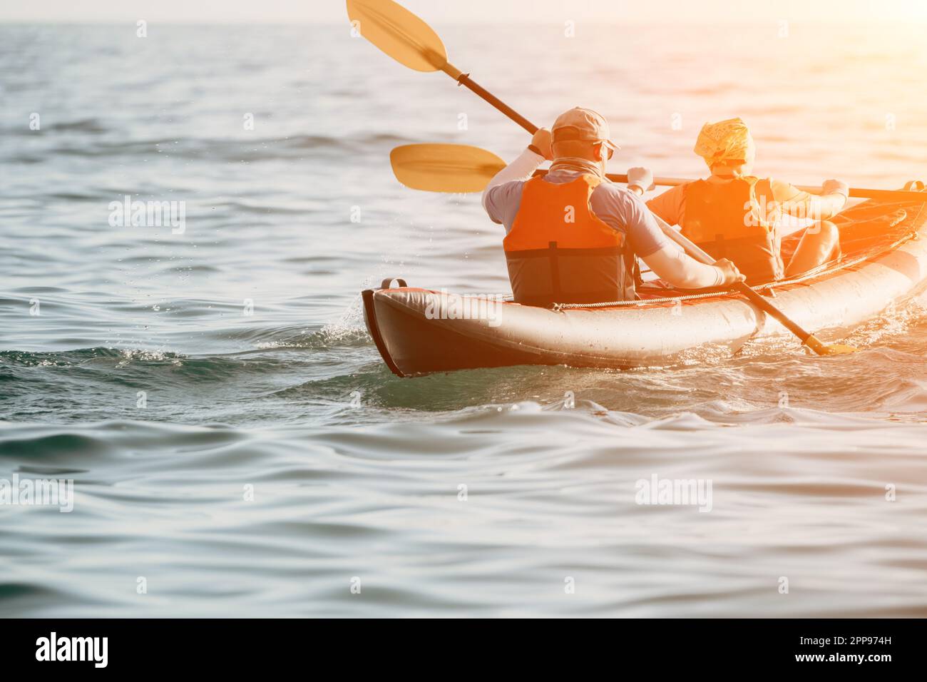 Happy couple kayaks in an inflatable kayak on the sea at sunset. Couple ...