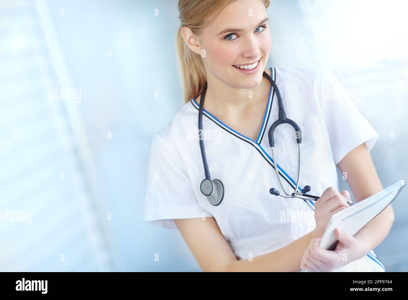 Getting your health details. Portrait of a smiling nurse writing notes ...
