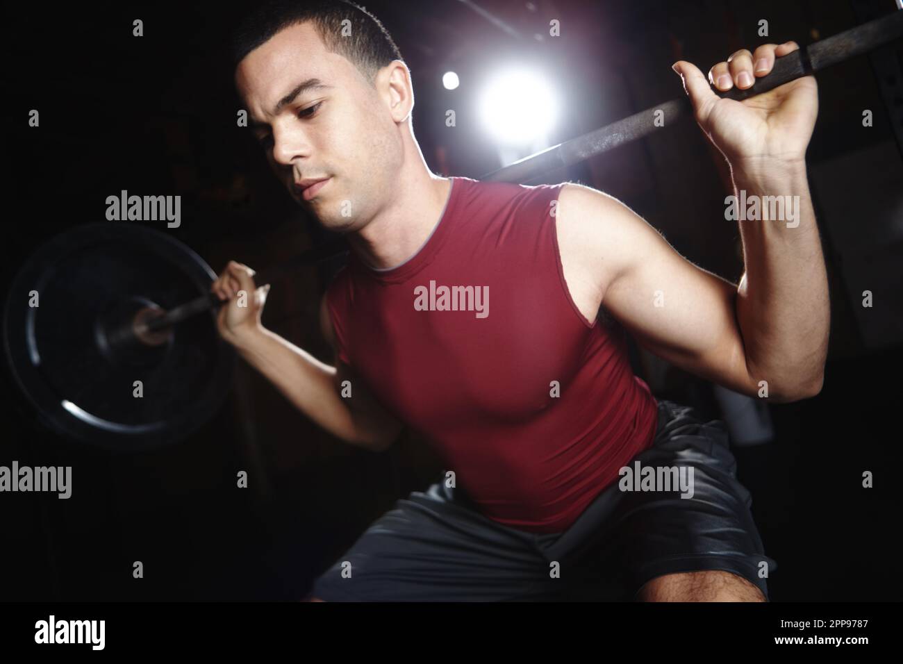Time for some serious lifting. A handsome young man lifting a barbell ...