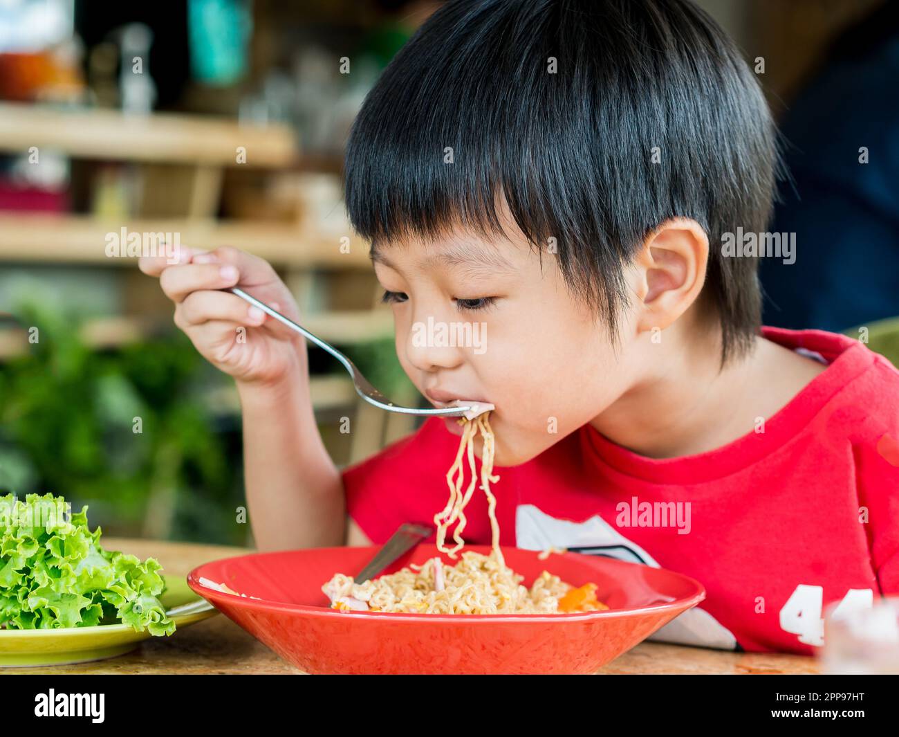 Happy Asian boy eating delicious noodle Stock Photo - Alamy