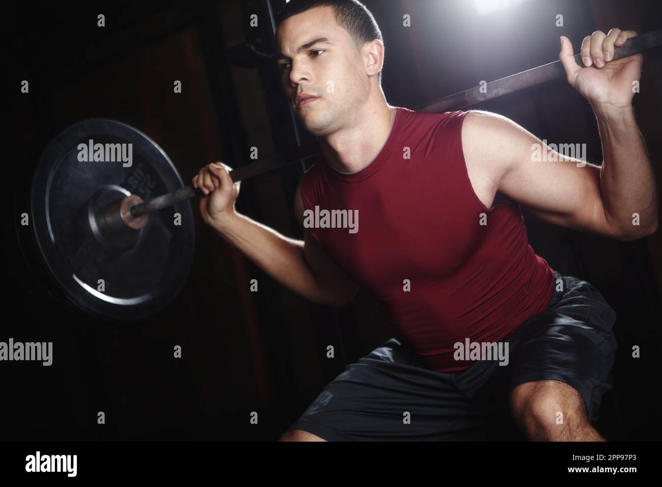 Hes got the power. A muscular young man lifting a barbell from a ...