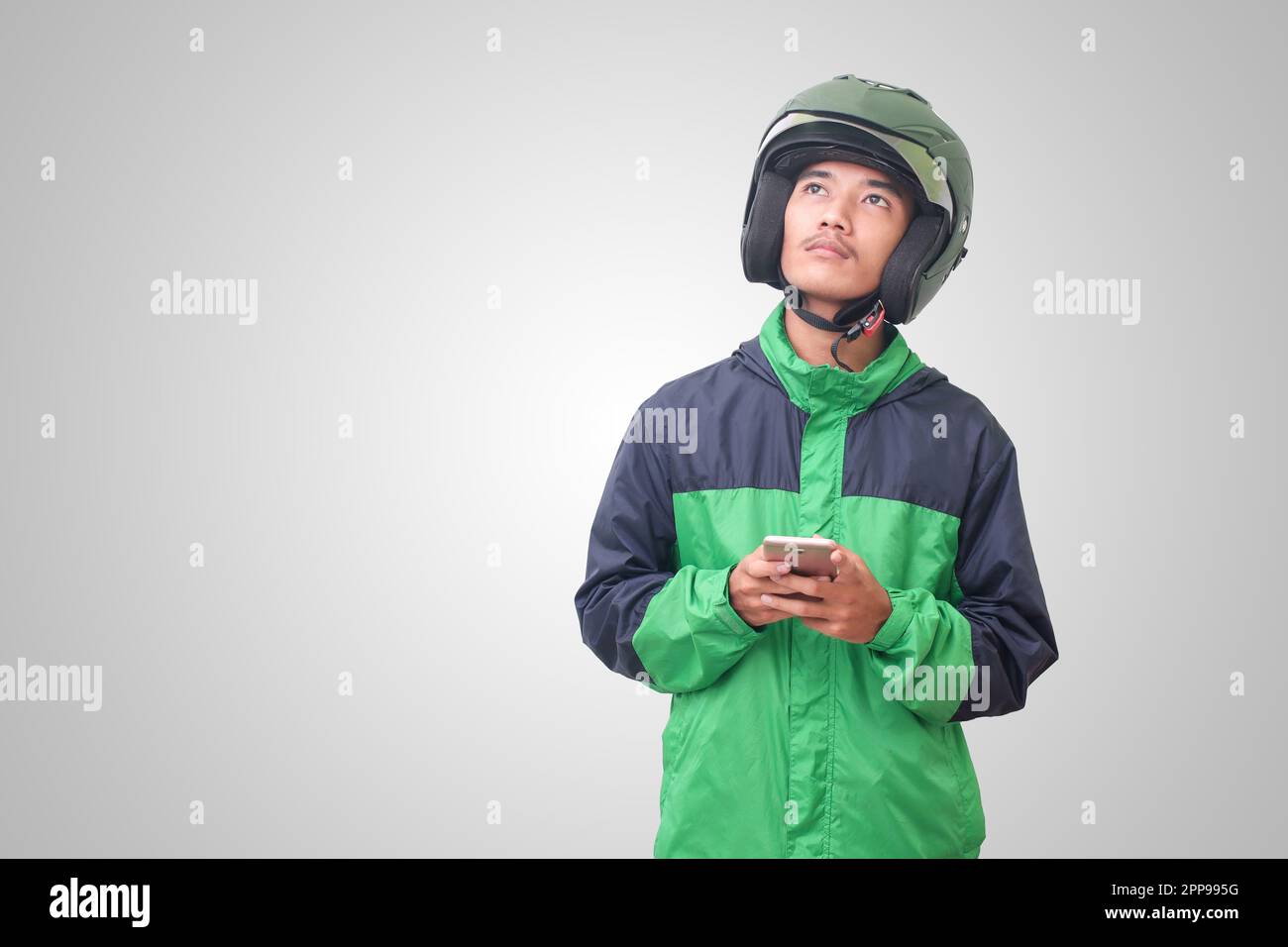 Portrait of confused Asian online taxi driver wearing green jacket and ...
