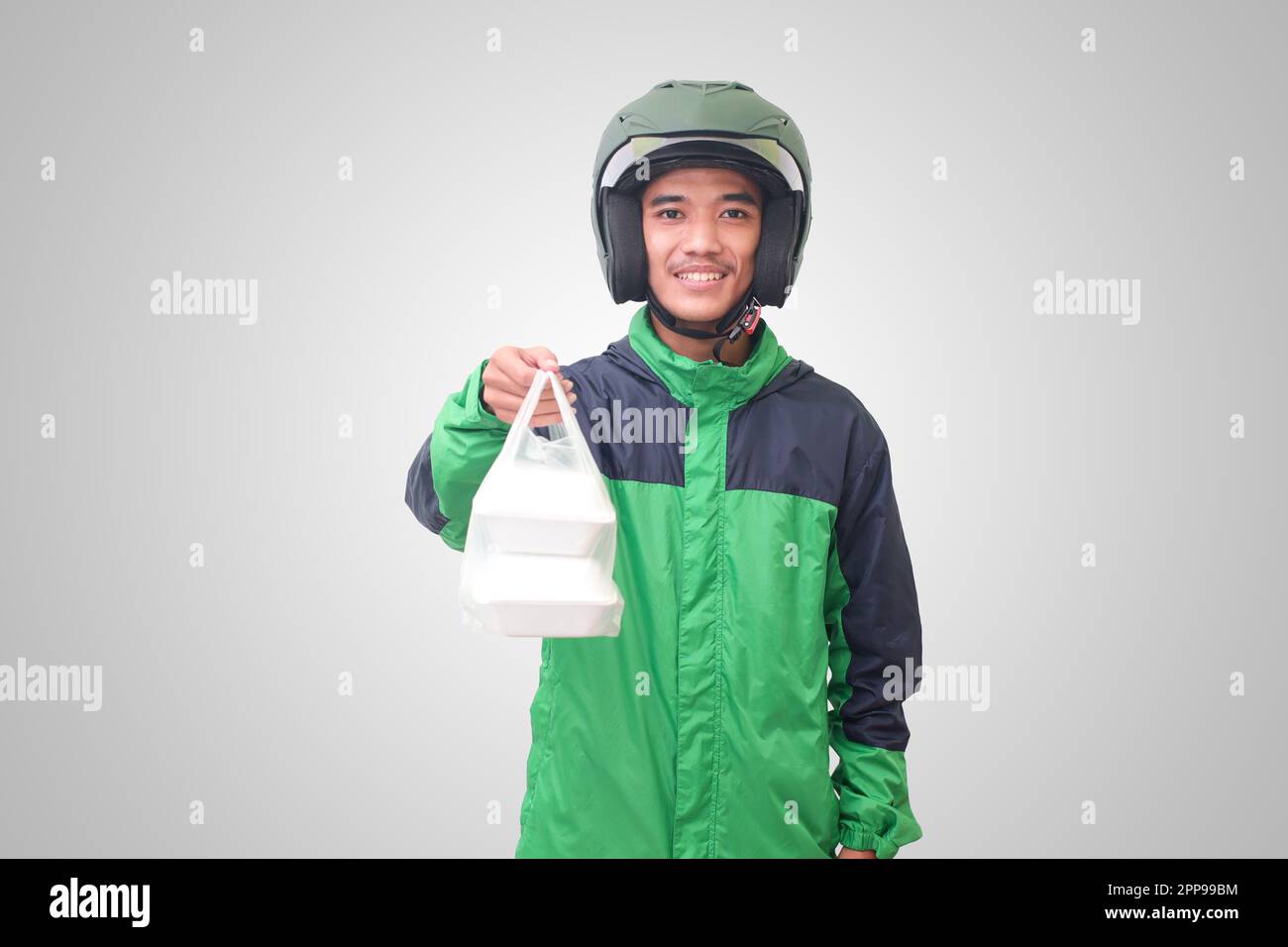 Portrait of Asian online taxi driver wearing green jacket and helmet ...