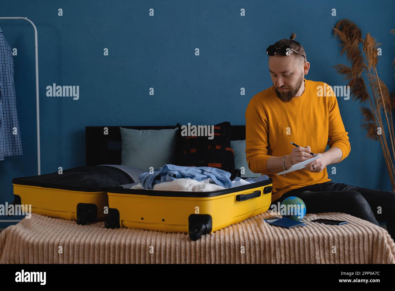 Handsome man writing checklist before holidays trip, people check ...