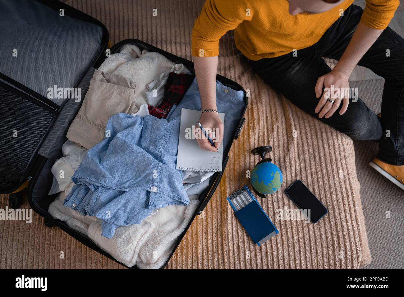 Making a check list of things to pack for travel. Top view of man ...