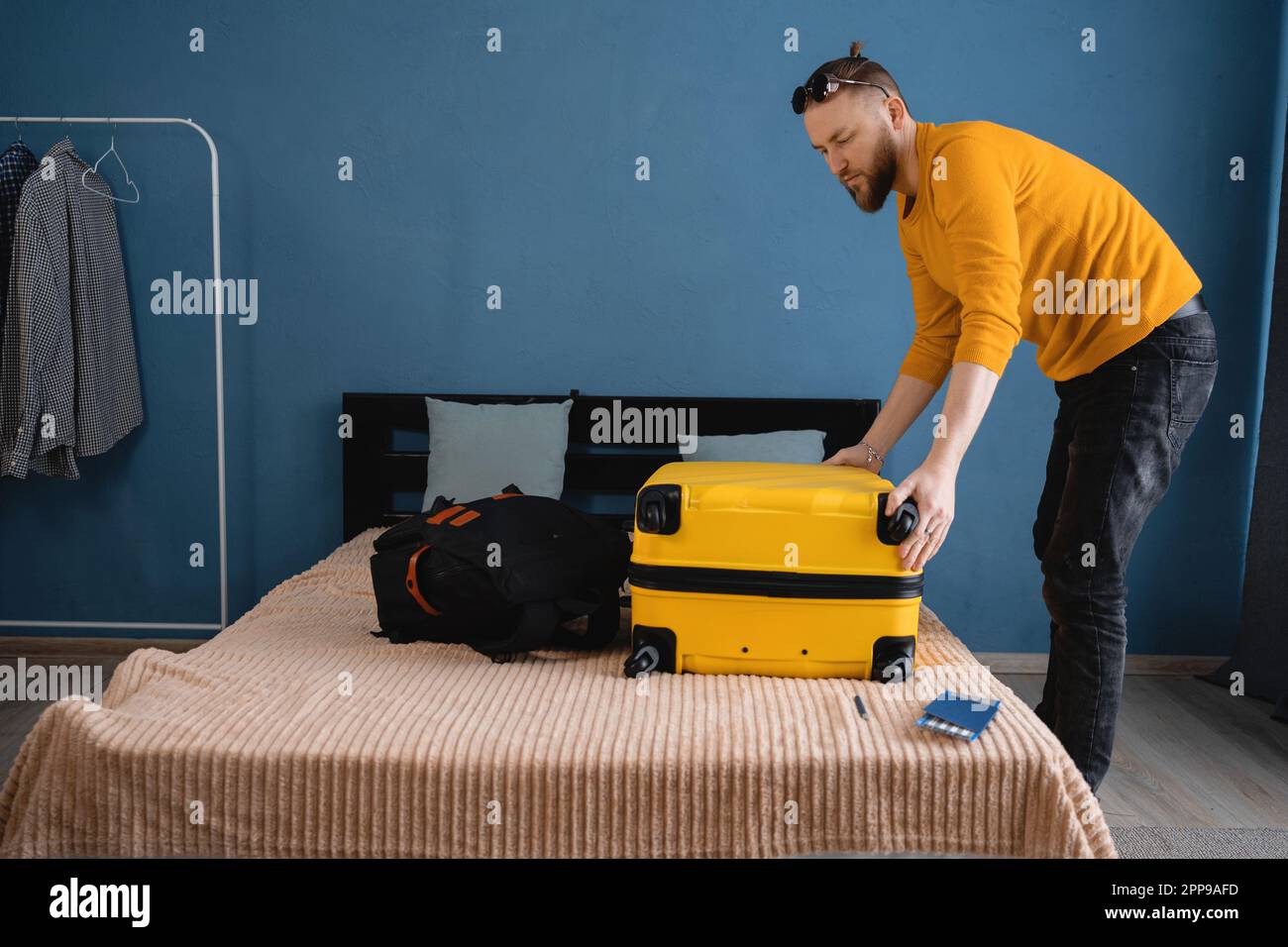 Vacation travel concept. Young man packing suitcase for summer journey ...