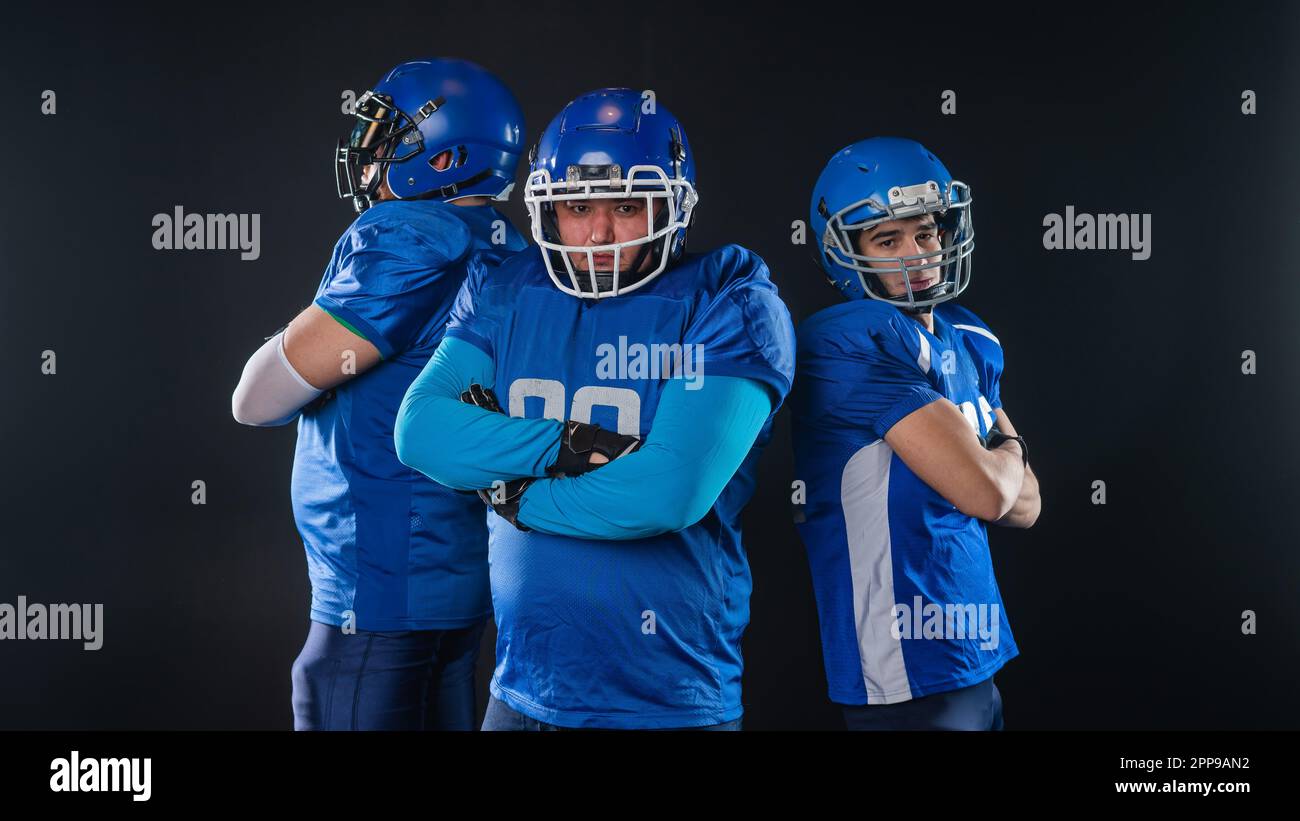 Portrait of three men in blue American football uniforms standing with ...