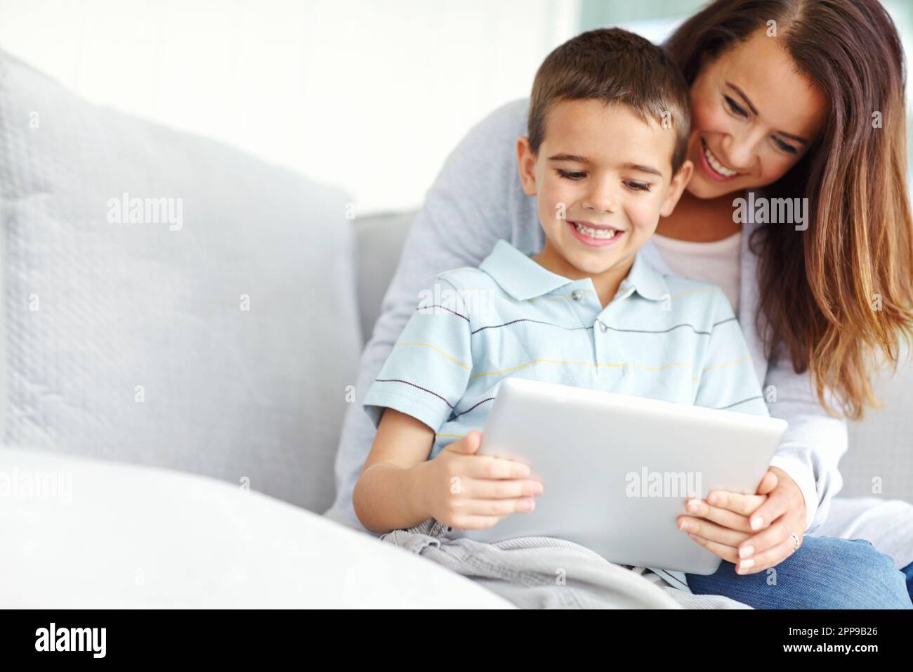 I need moms help. A mother helping her son use a digital tablet Stock ...
