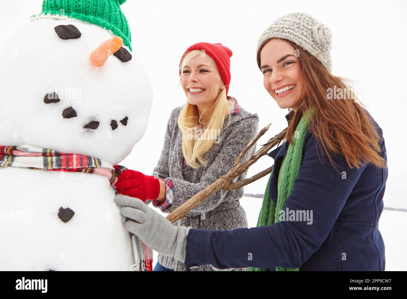 Placing the finishing touches on their snowman. two beautiful young ...