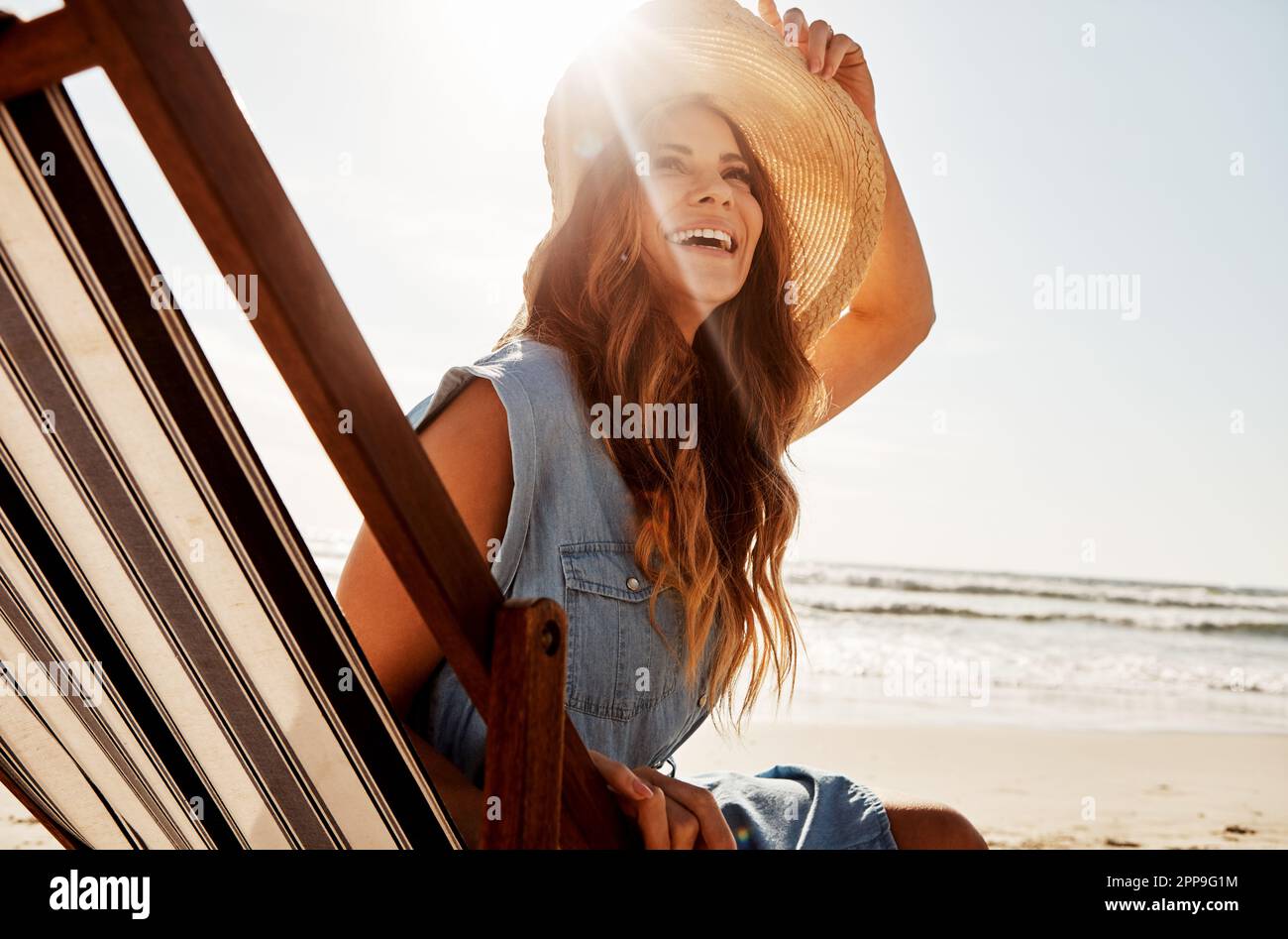 Hello mister sunshine. a young woman relaxing on a lounger at the beach ...