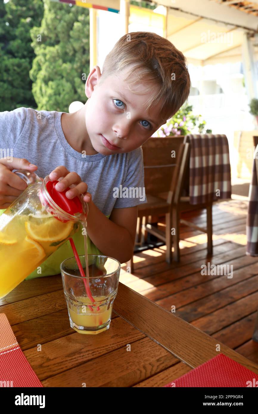 Child pouring lemonade from jug into glass in restaurant Stock Photo ...