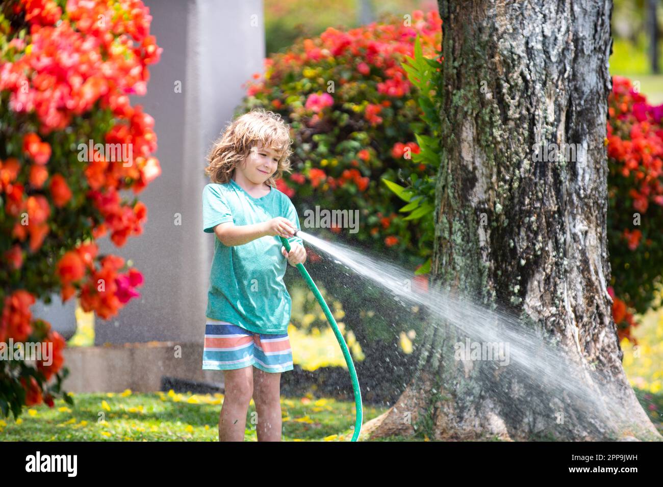 Funny kid playing with garden hose in backyard. Child having fun with ...