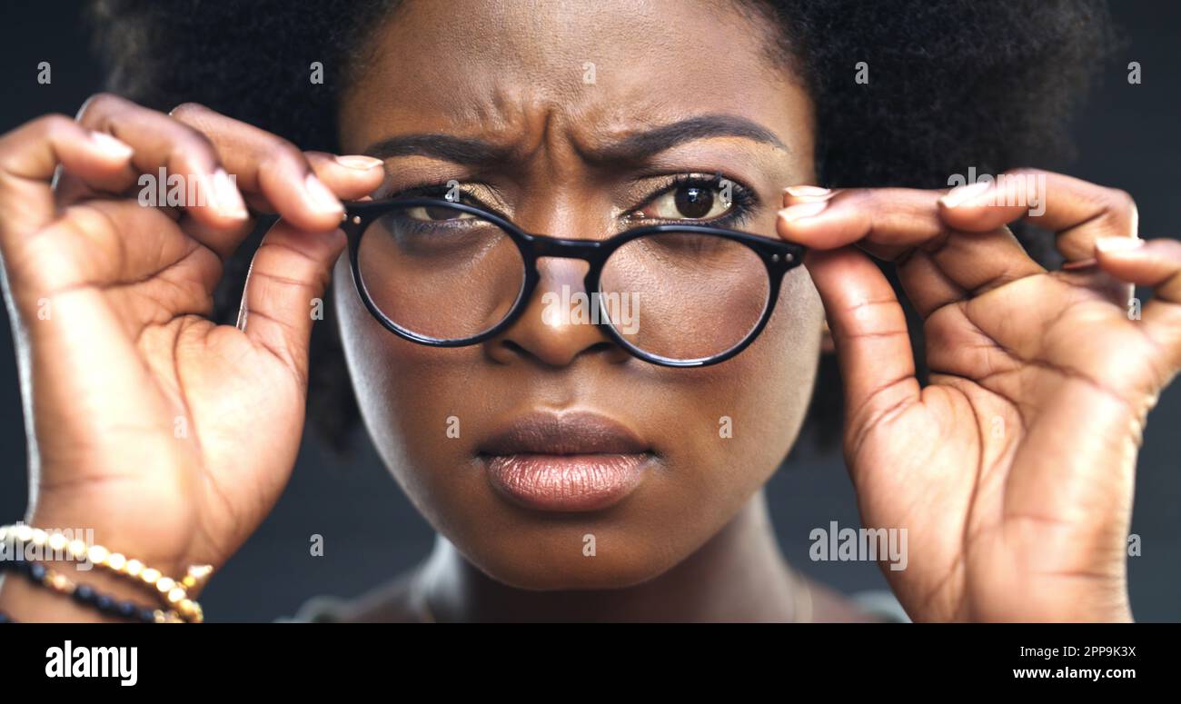 I hope you visited your optometrist this year. a woman adjusting her glasses against a dark ...