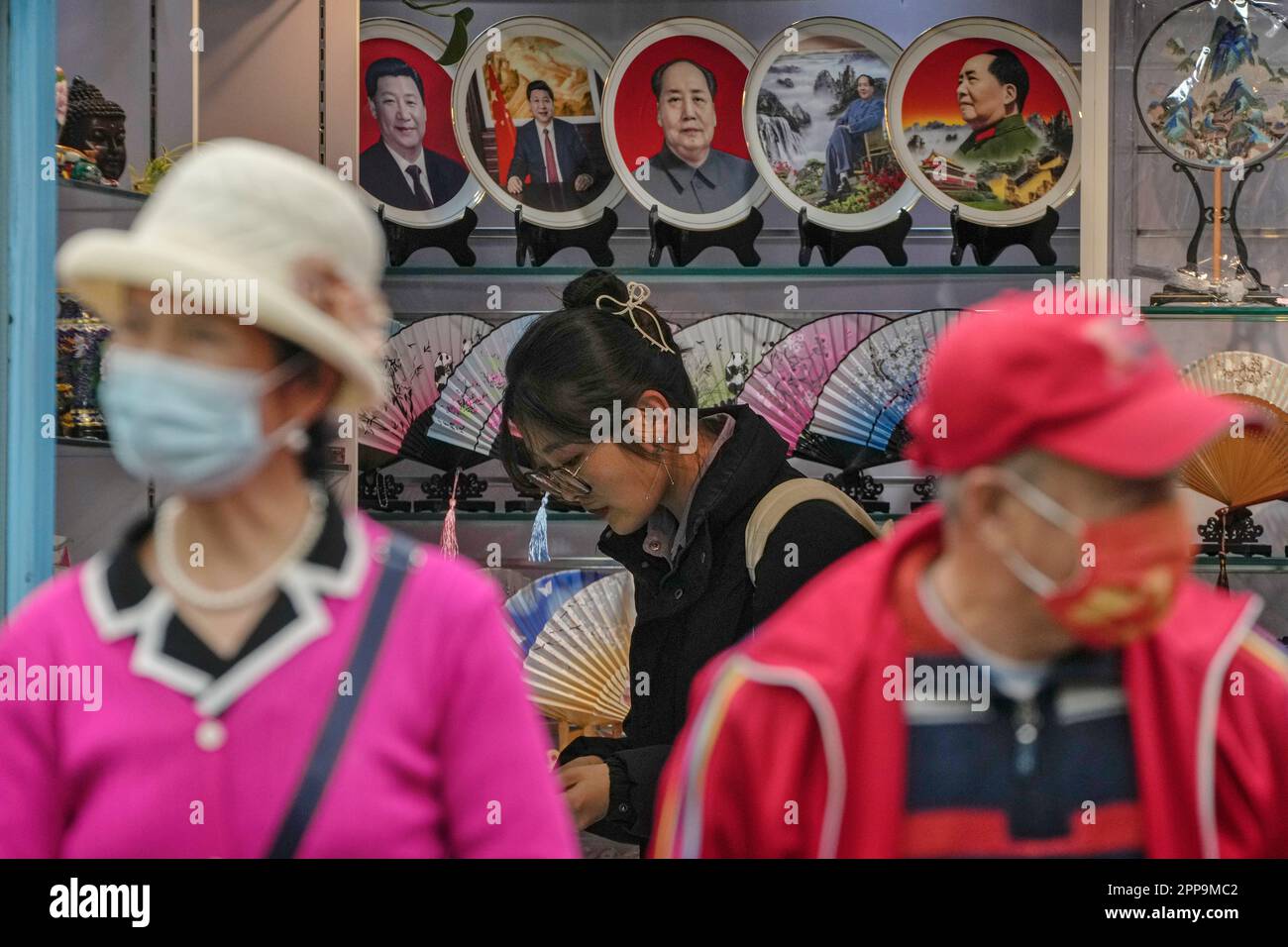 People wearing face masks stand as a woman shops at a store selling ...