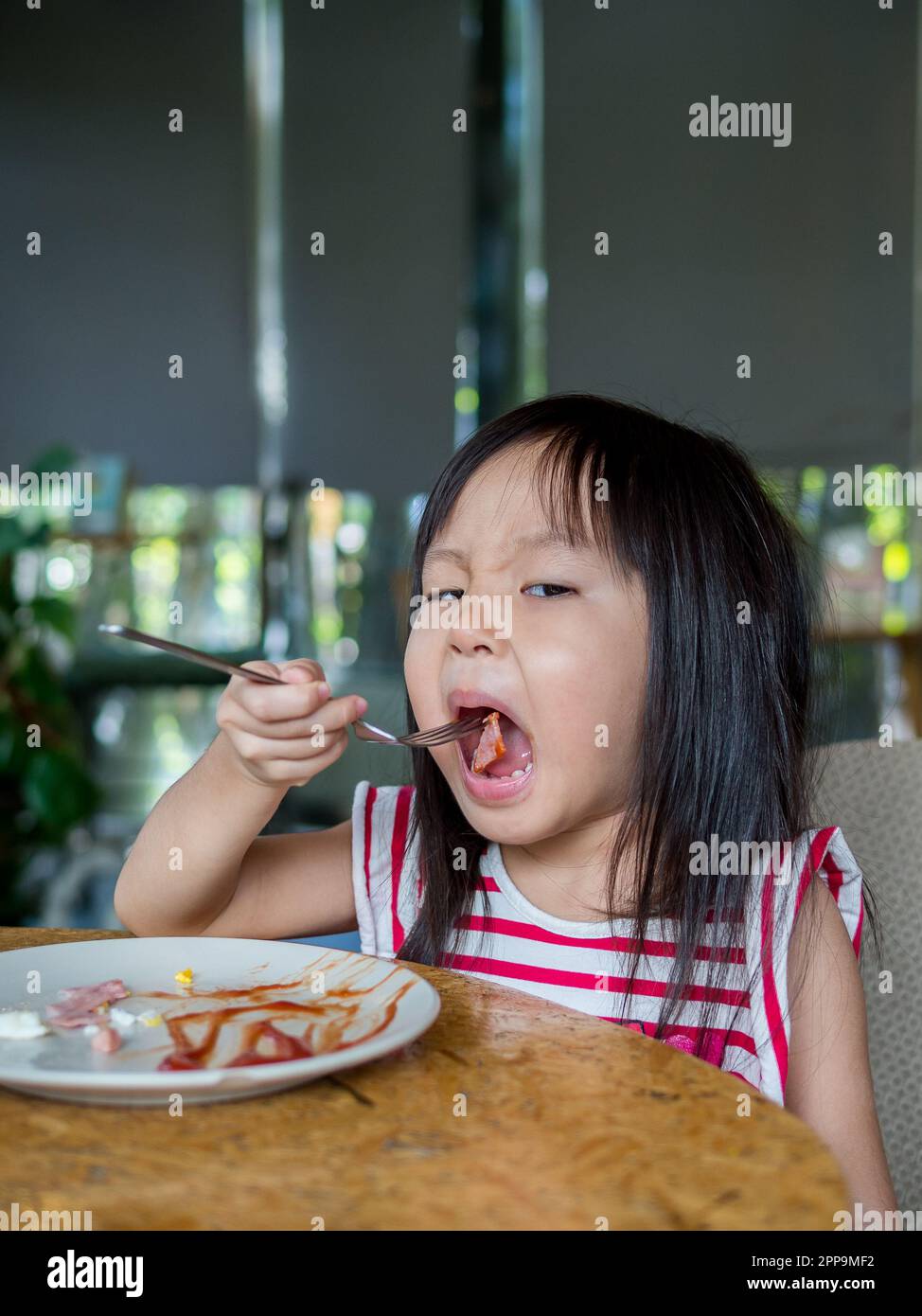 Asian girl child eating american breakfast Stock Photo - Alamy