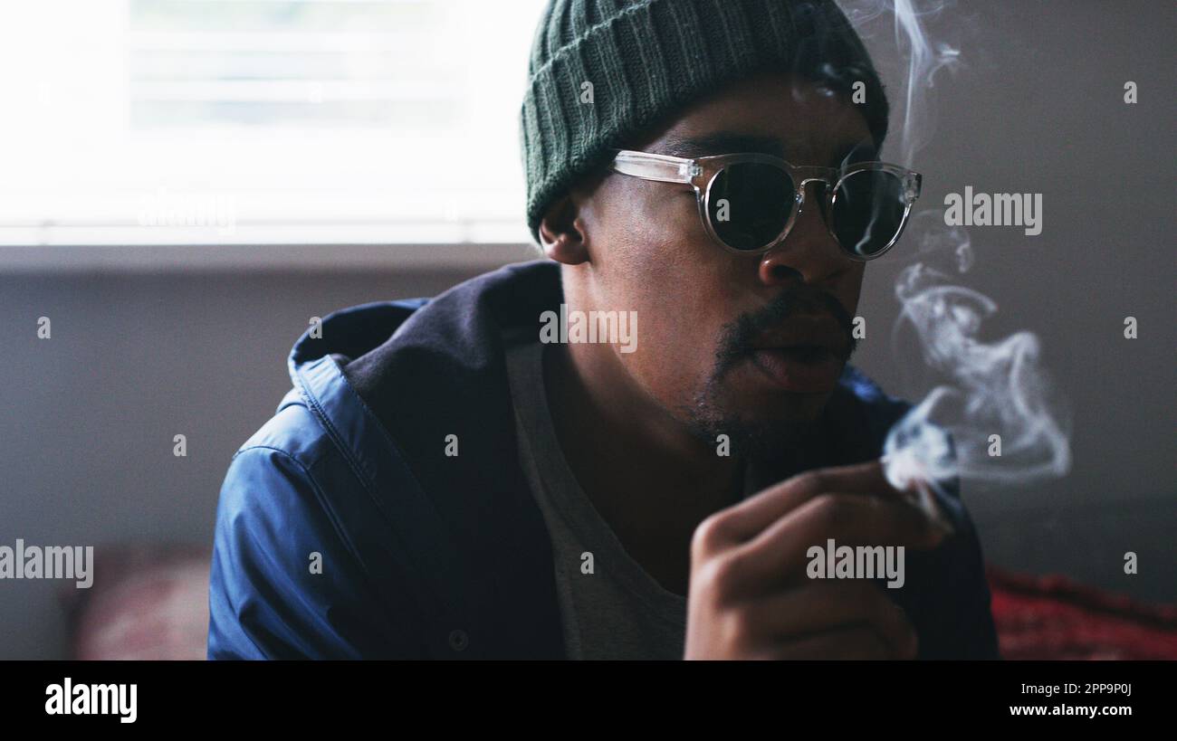 He prefers to smoke alone. a young man smoking a marijuana joint at ...