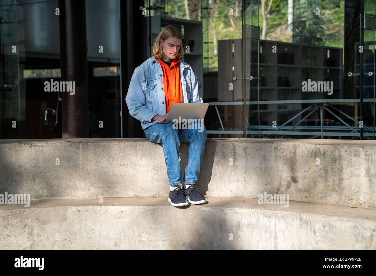 Concentrated self-sufficient man with laptop sits near building works ...